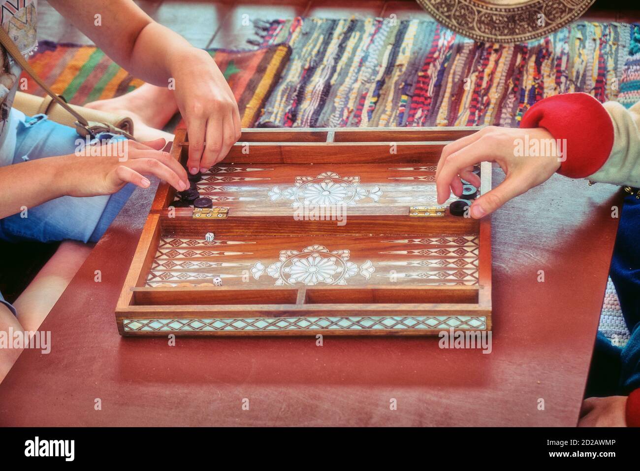 Hands of backgammon players. Two people are playing at the retro board ...