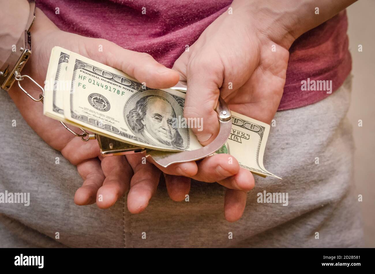 Men's hands in handcuffs behind their backs, holding dollars. concept ...
