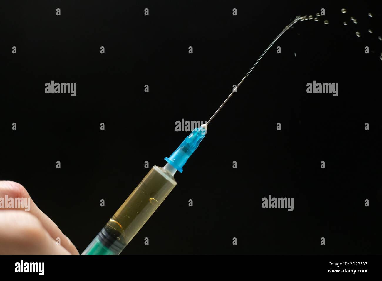Syringe with injection drops on a black background with a copy of the ...