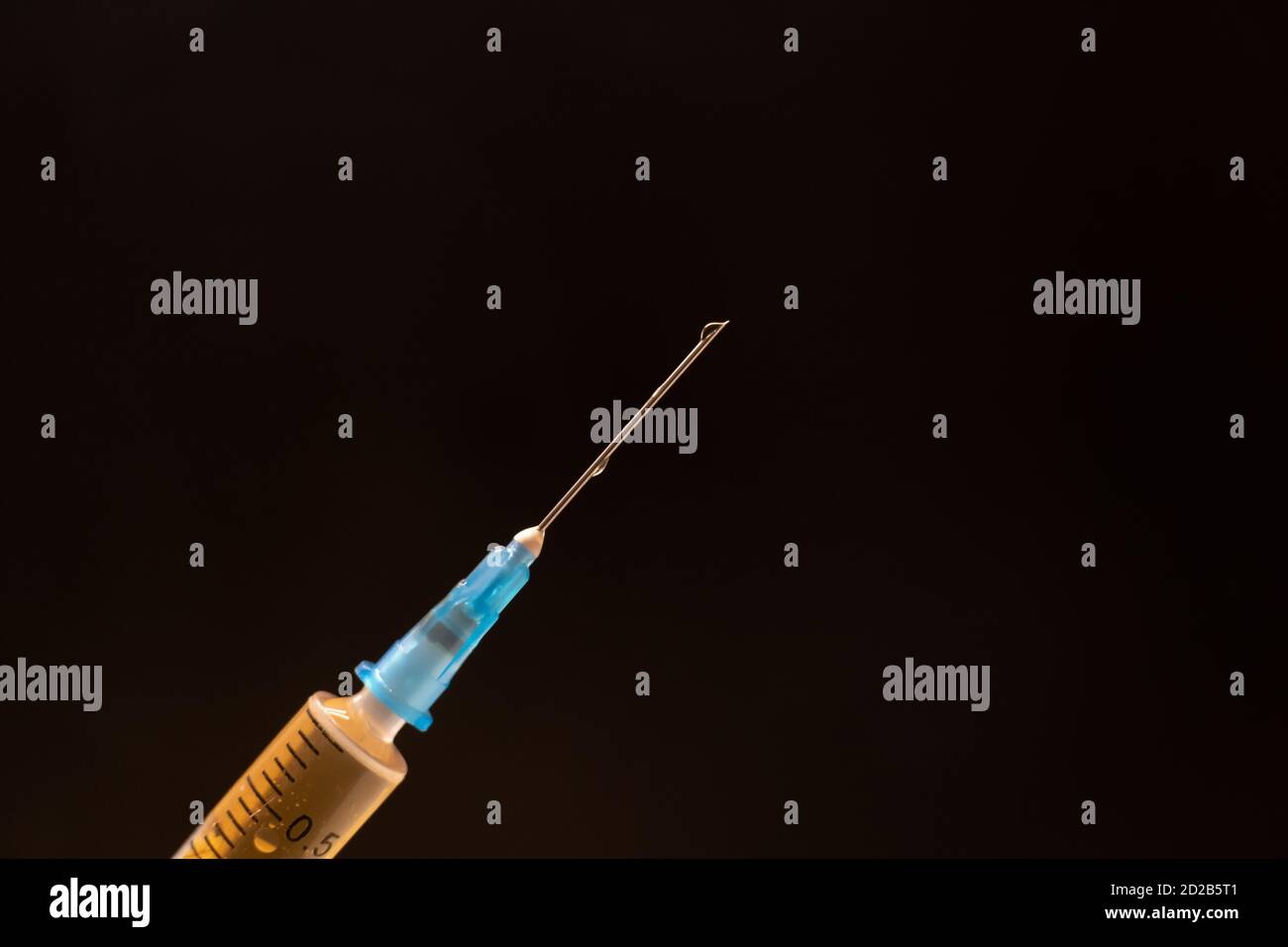 Syringe with injection drops on a black background with a copy of the ...