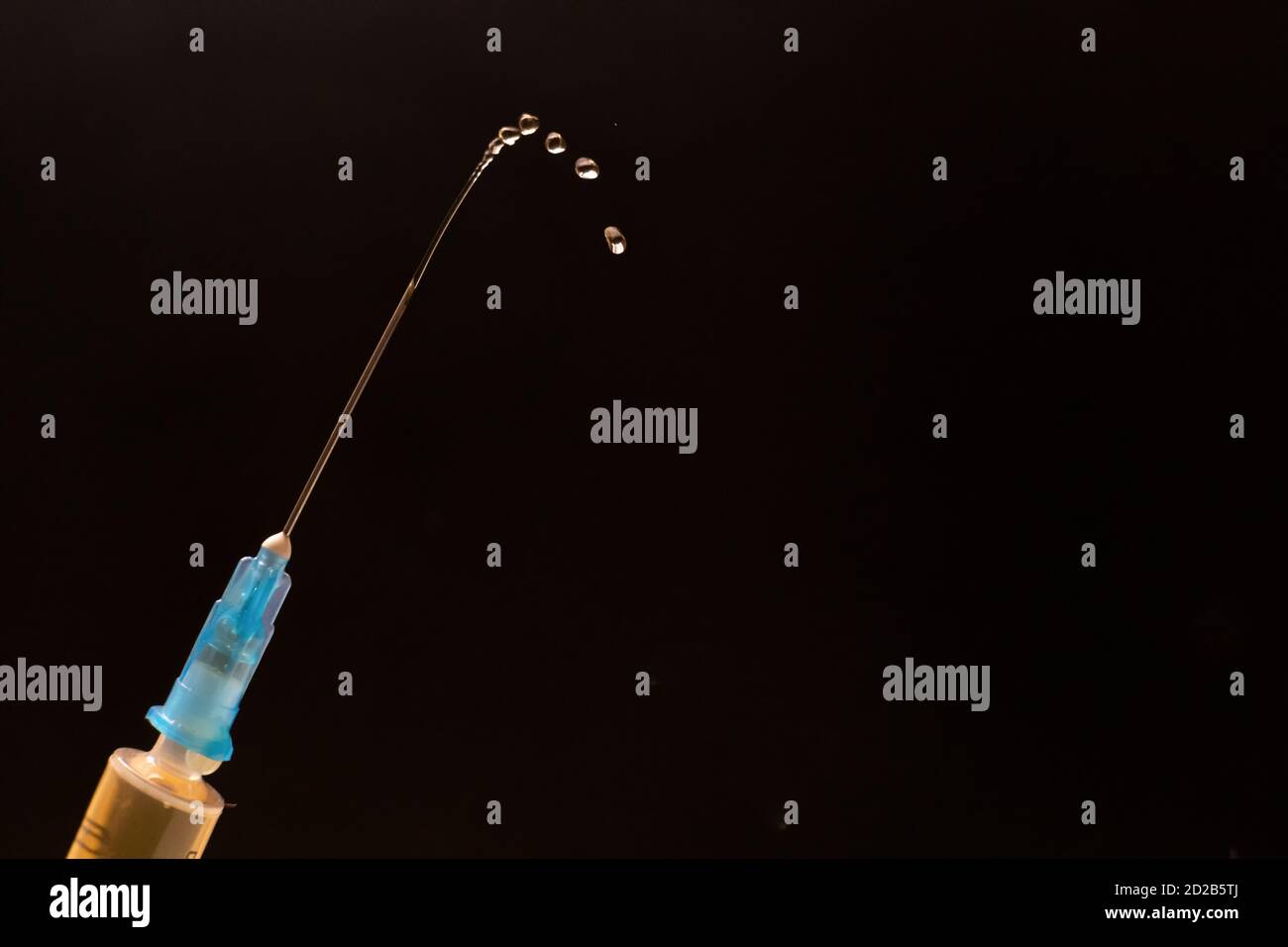Syringe with injection drops on a black background with a copy of the ...
