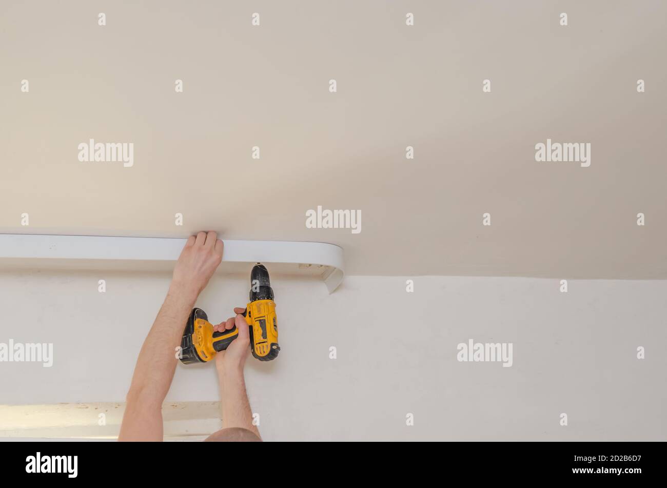 Fastening to the wall guide for stretch ceiling. Repairers make ...