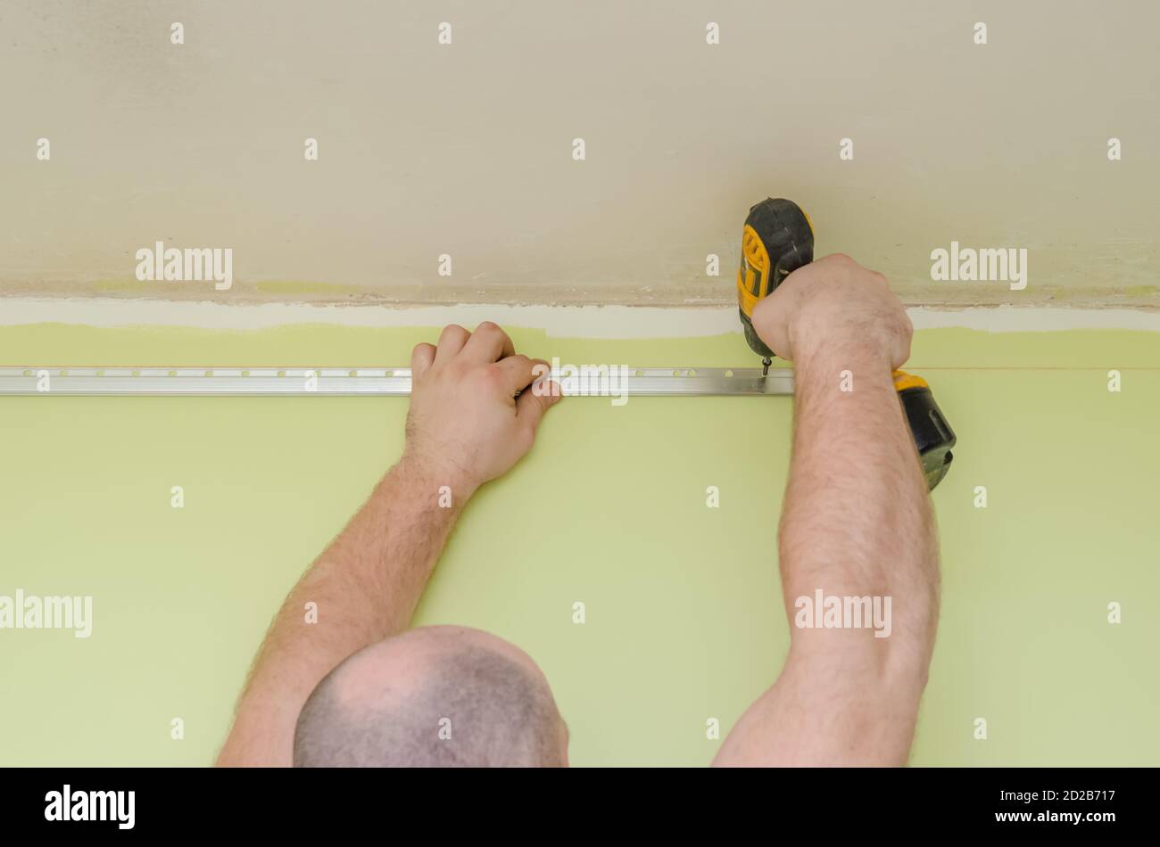 Fastening to the wall guide for stretch ceiling. Repairers make ...