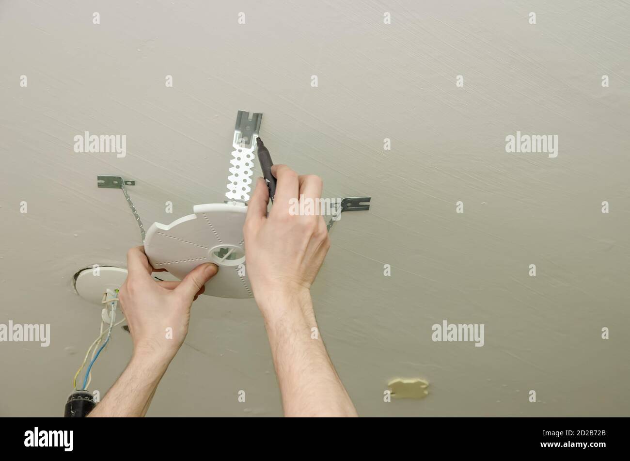 repairman installs a platform under a lamp for a stretch ceiling close ...