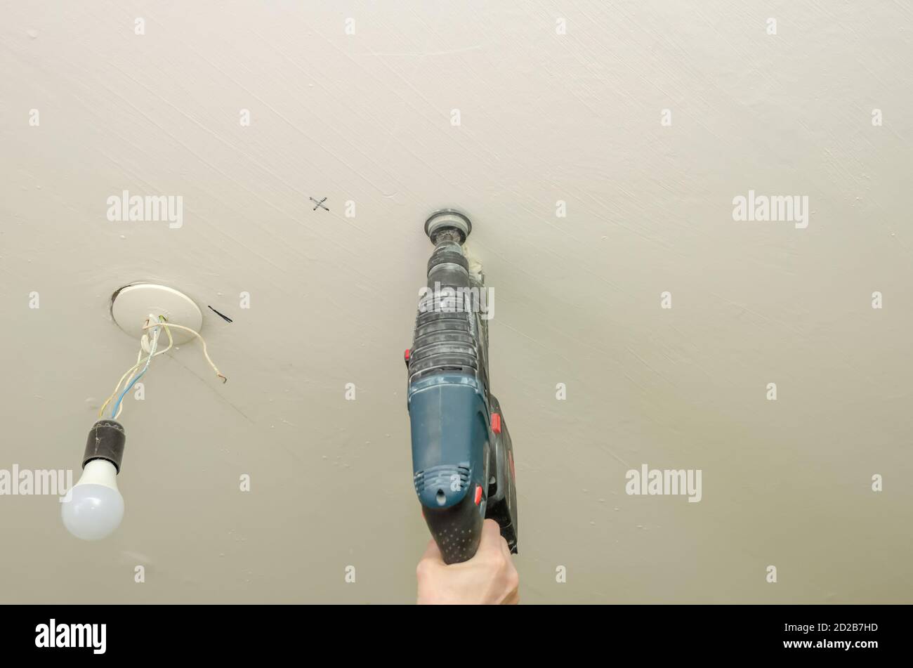 repairman installs a platform under a lamp for a stretch ceiling close ...