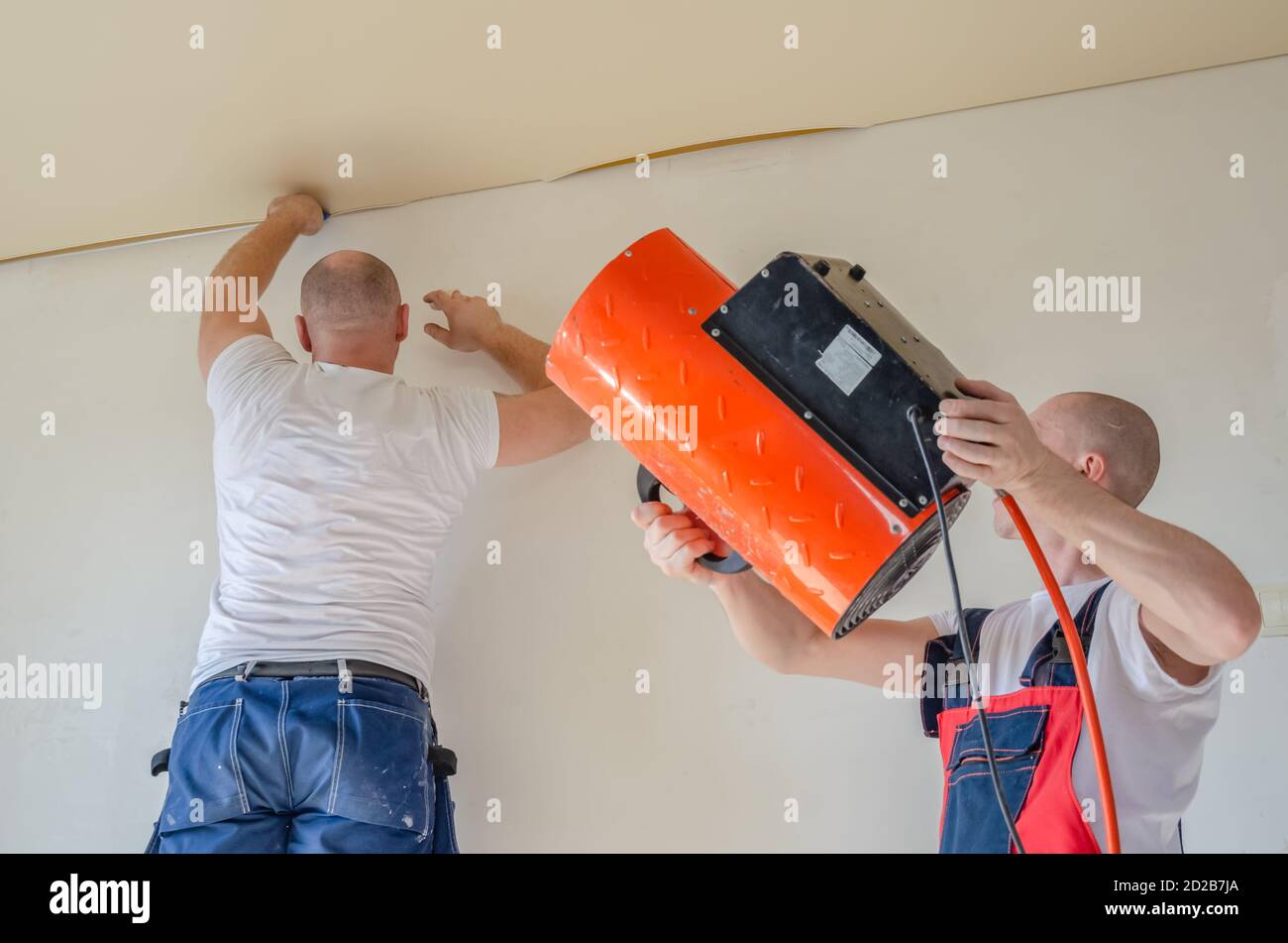 Repairers stretch the stretch ceiling with a gas heat gun Stock Photo ...