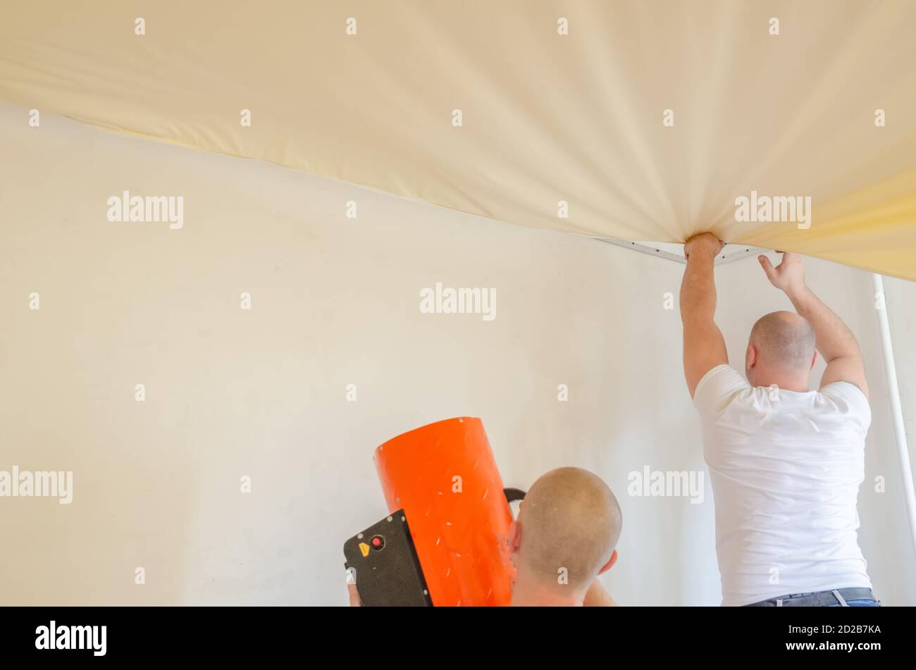Repairers stretch the stretch ceiling with a gas heat gun Stock Photo ...
