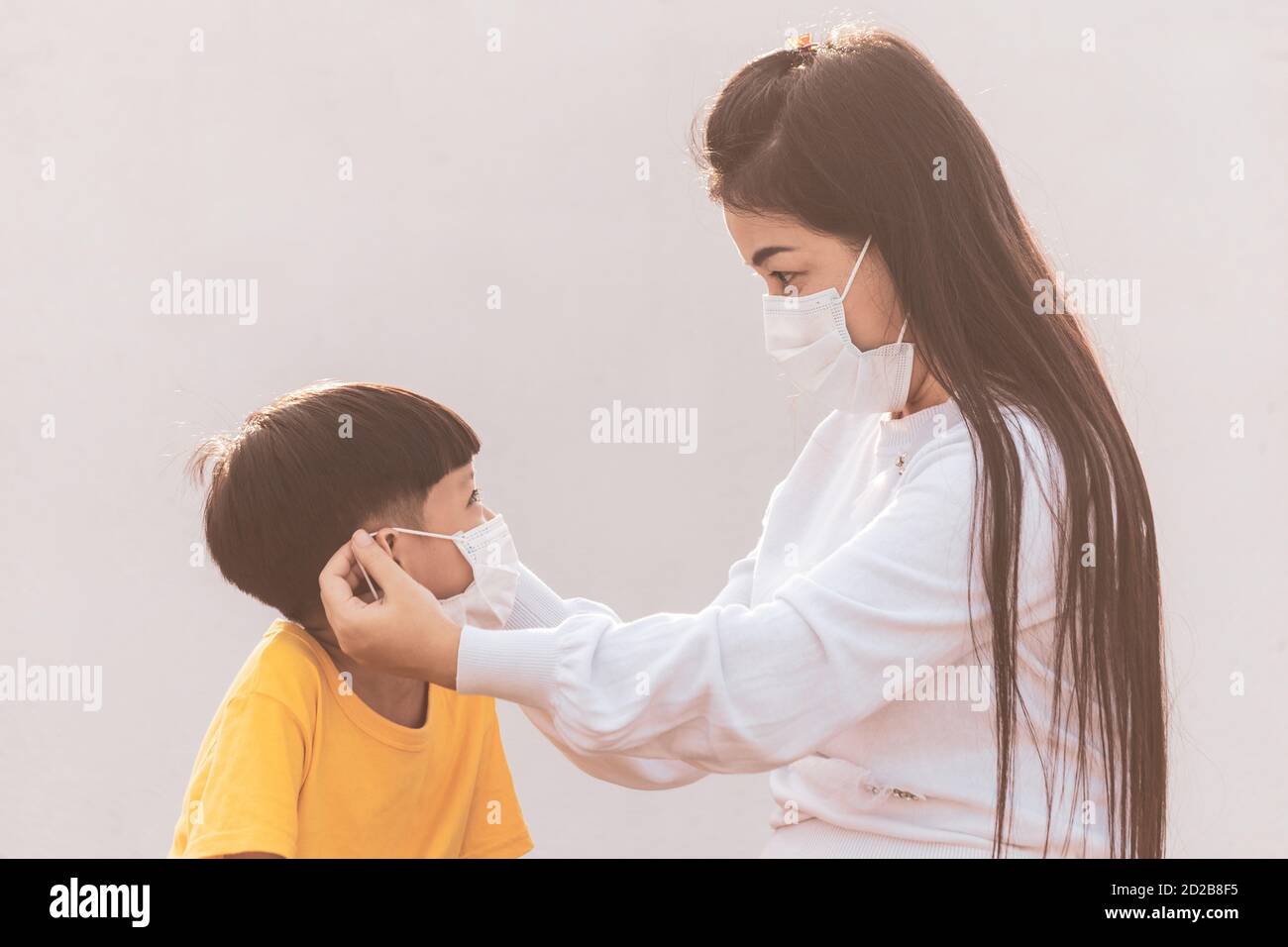 Mom is wearing a medical mask for her child. Little asian boy and mom ...