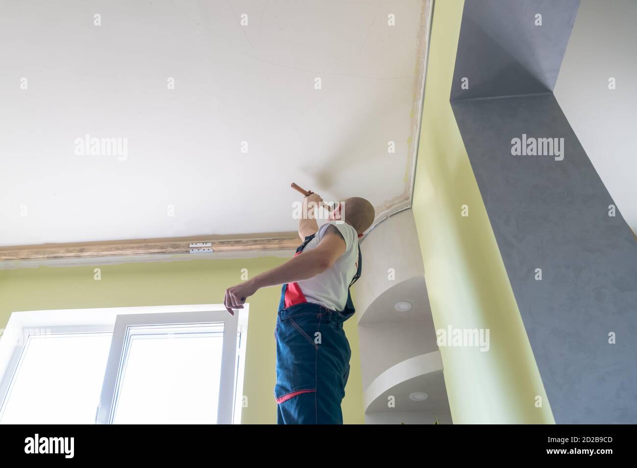 Worker knocks on the ceiling with a hammer, wiring installation Stock ...