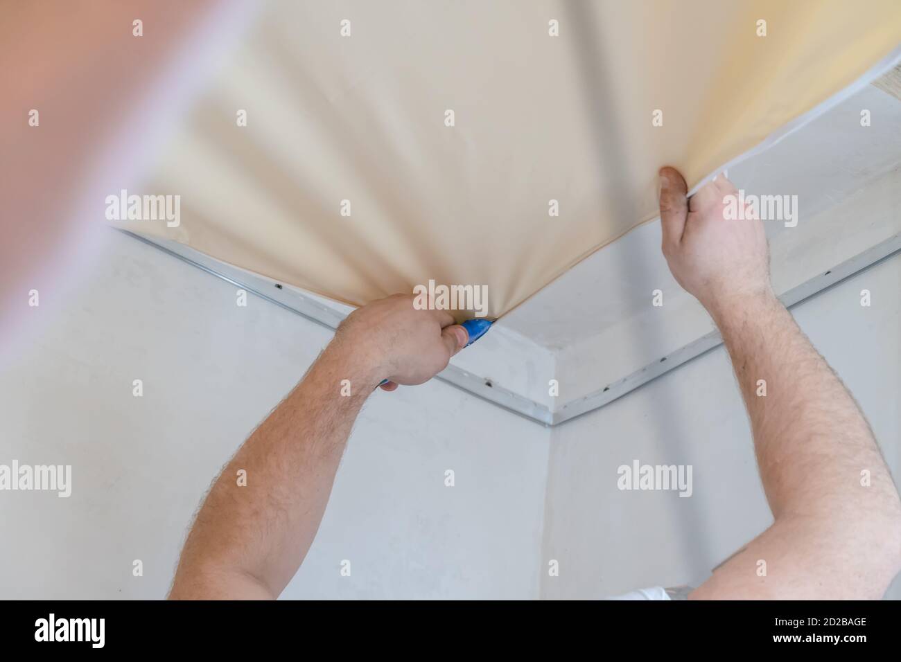 Repairers make installation of a stretch ceiling Stock Photo - Alamy