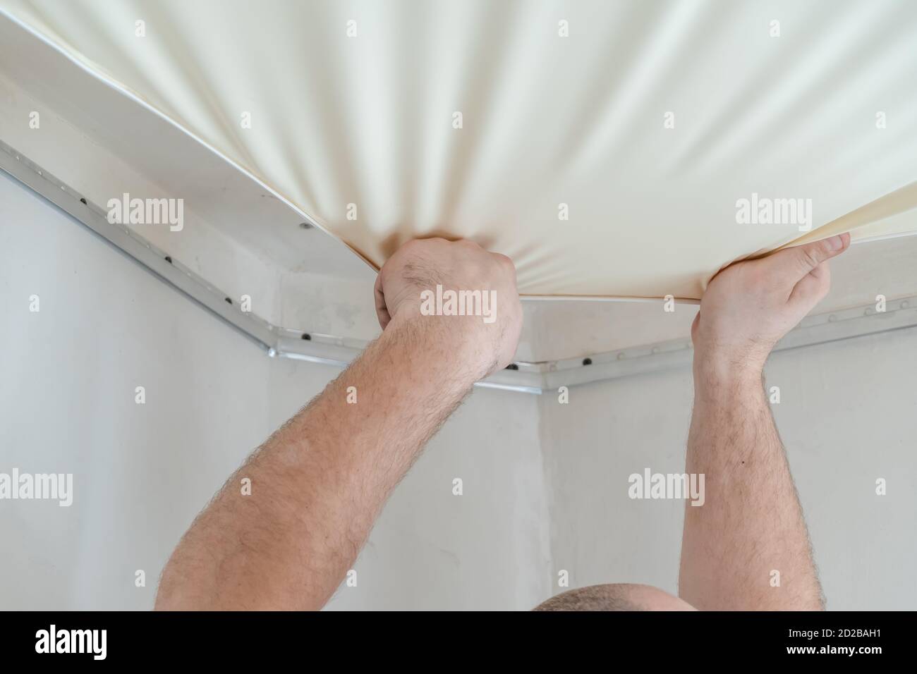 Repairers make installation of a stretch ceiling Stock Photo - Alamy