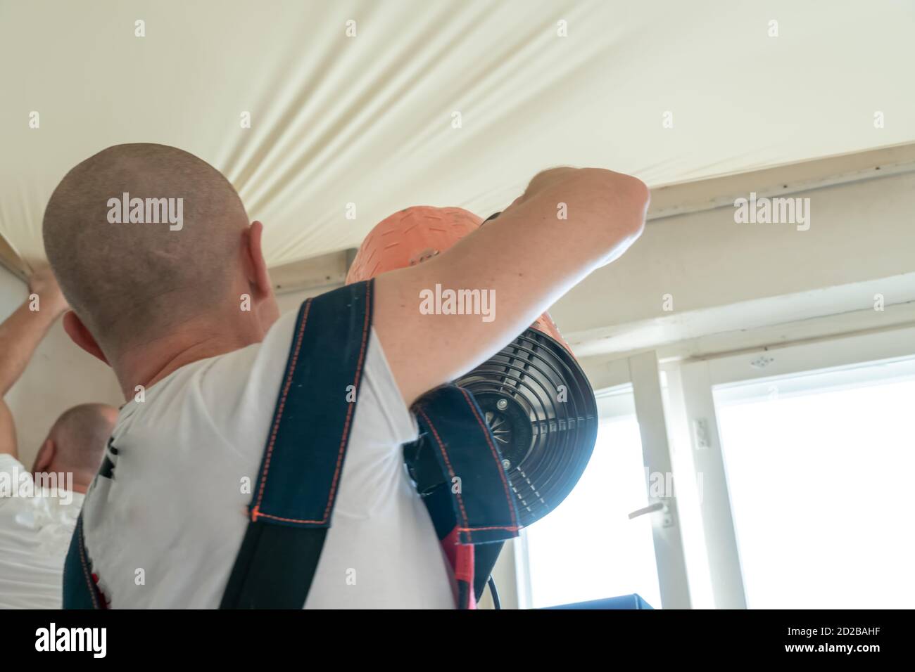 Repairers stretch the stretch ceiling with a gas heat gun Stock Photo ...