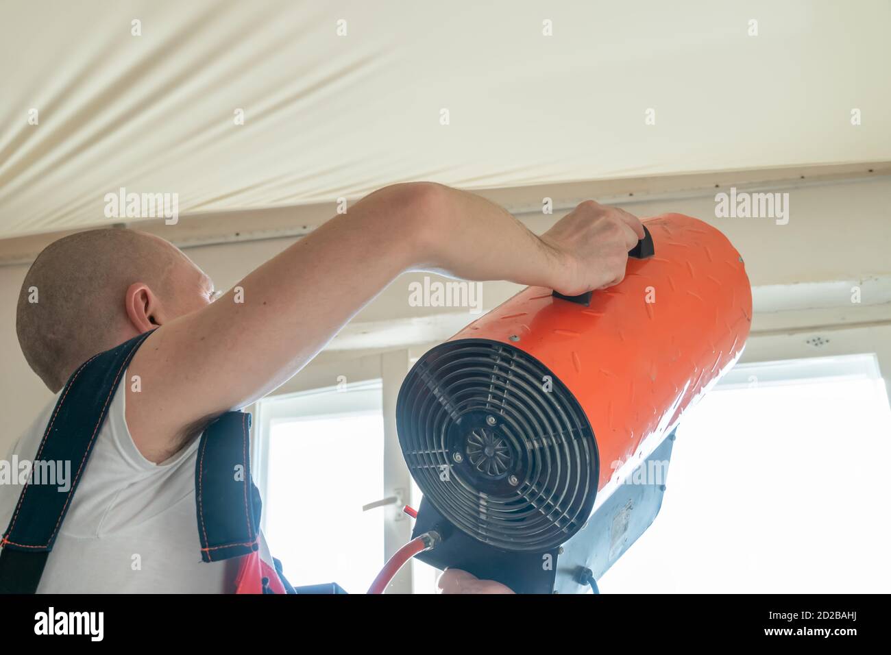 Repairers stretch the stretch ceiling with a gas heat gun Stock Photo ...