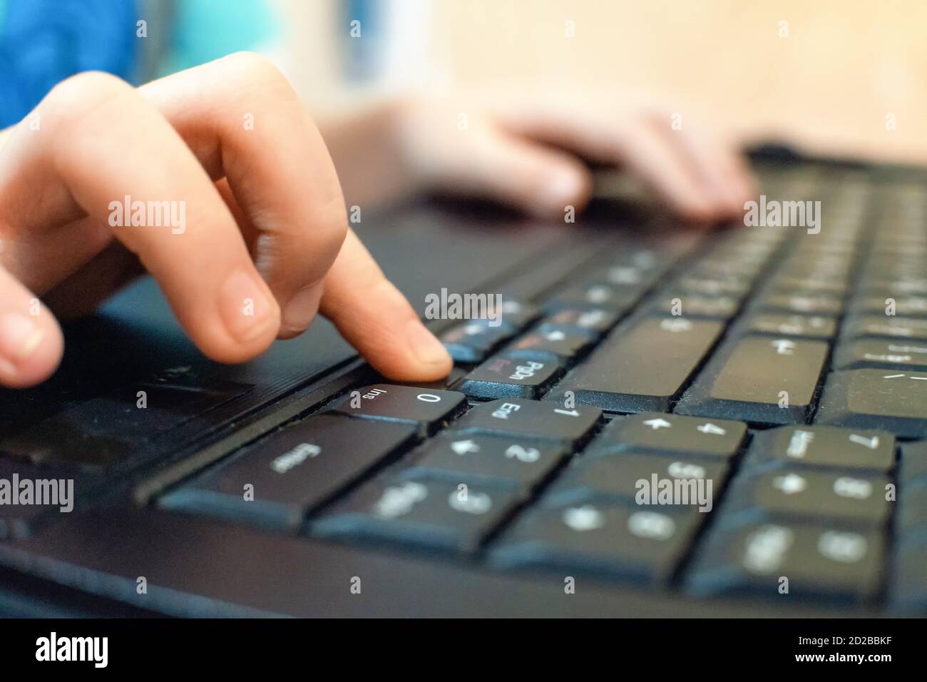 Small hand of a child on the laptop keyboard close-up. A child is ...