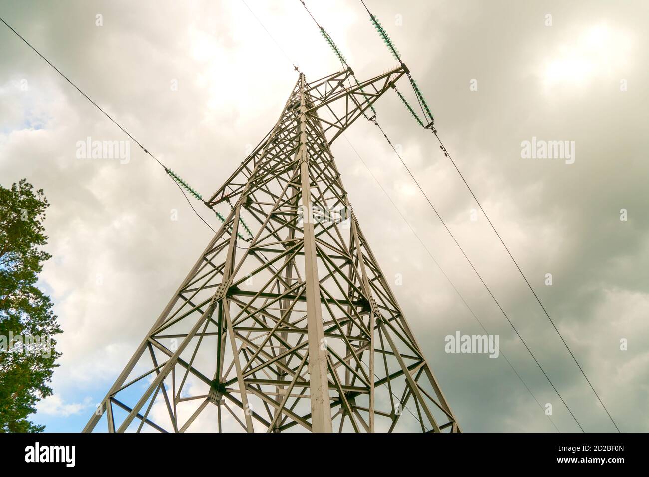 High-voltage power line against a cloudy sky with flashes of blue sky ...
