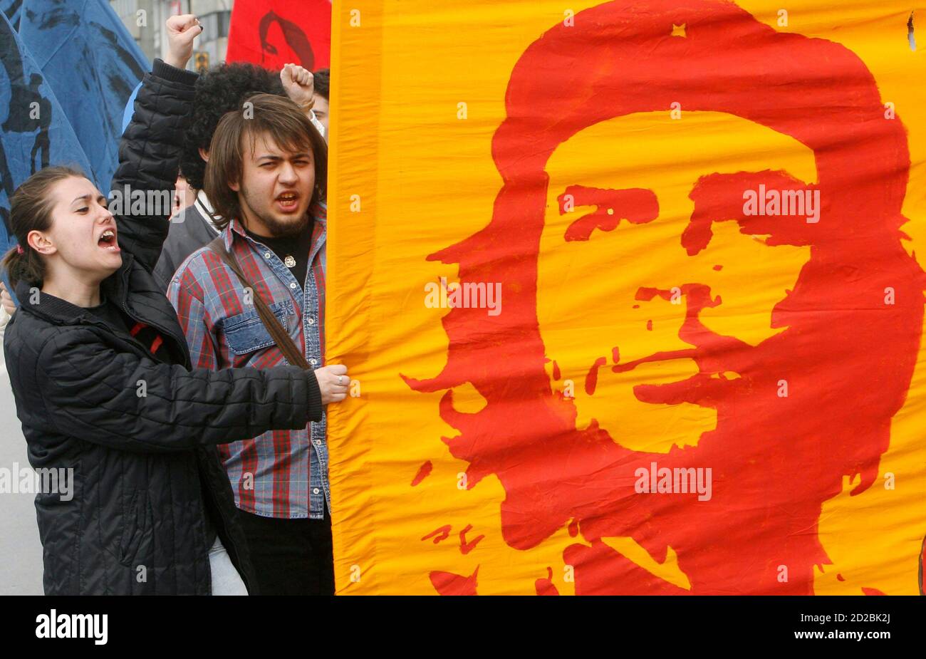 Demonstrators standing beside a banner depicting Ernesto "Che" Guevara ...