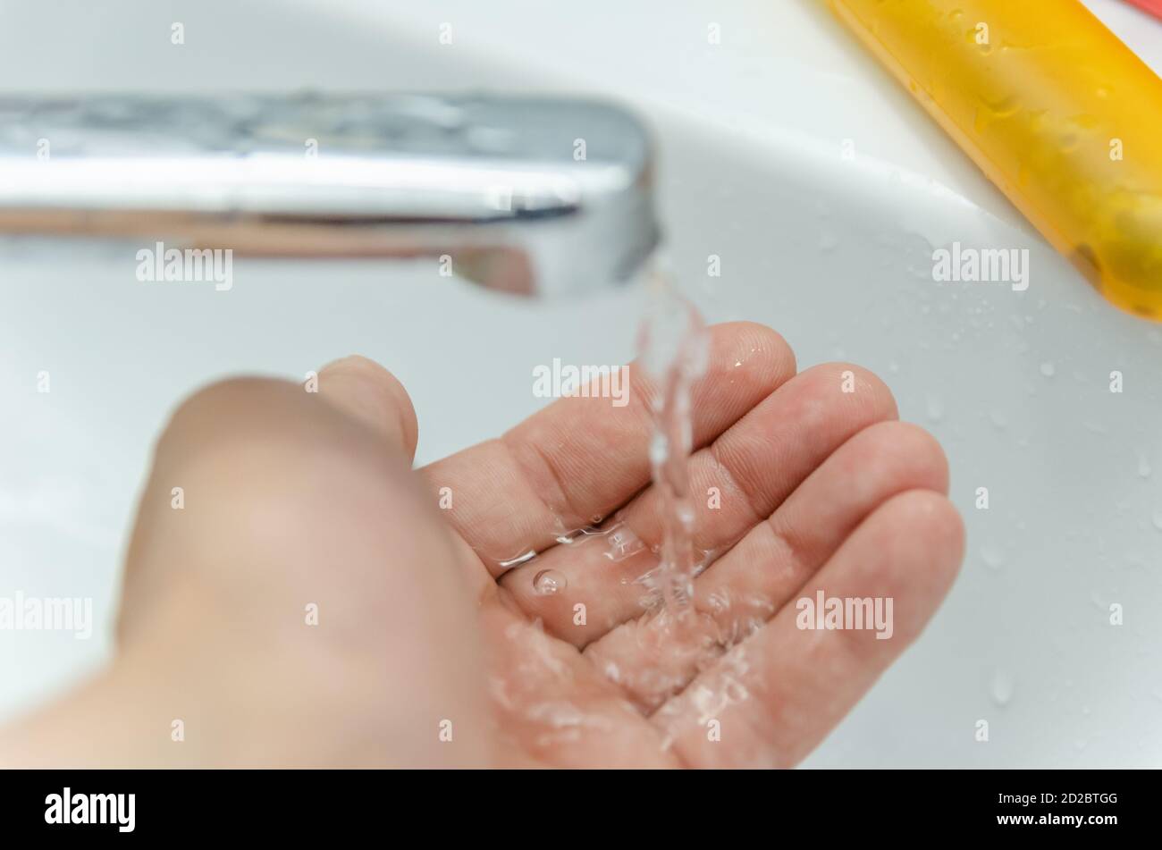 Male hand close-up under water tap in bathroom Stock Photo - Alamy