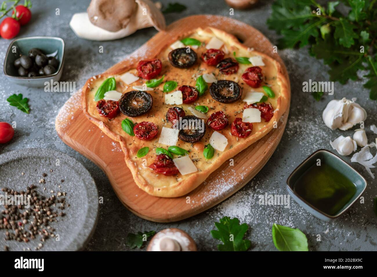 Pizza with tomatoes, mushrooms, and parmesan cheese in an irregular ...