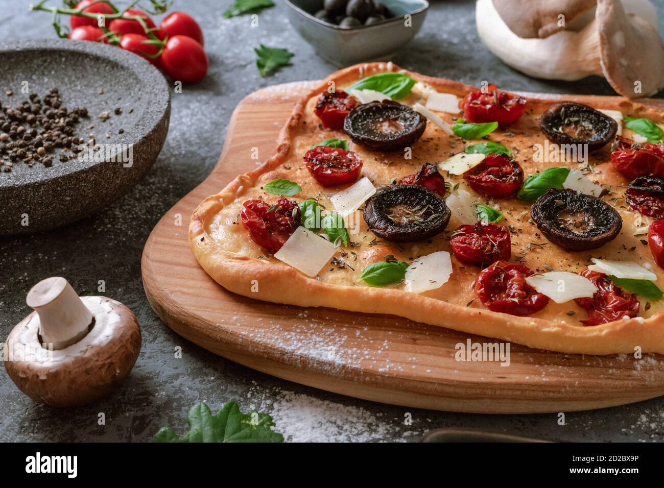 Pizza with tomatoes, mushrooms, and parmesan cheese in an irregular ...
