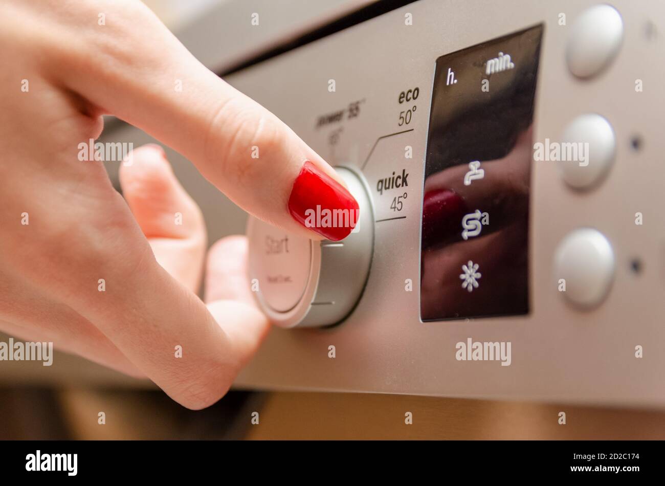 A woman's hand with red nail Polish lights a gray kitchen gas stove ...