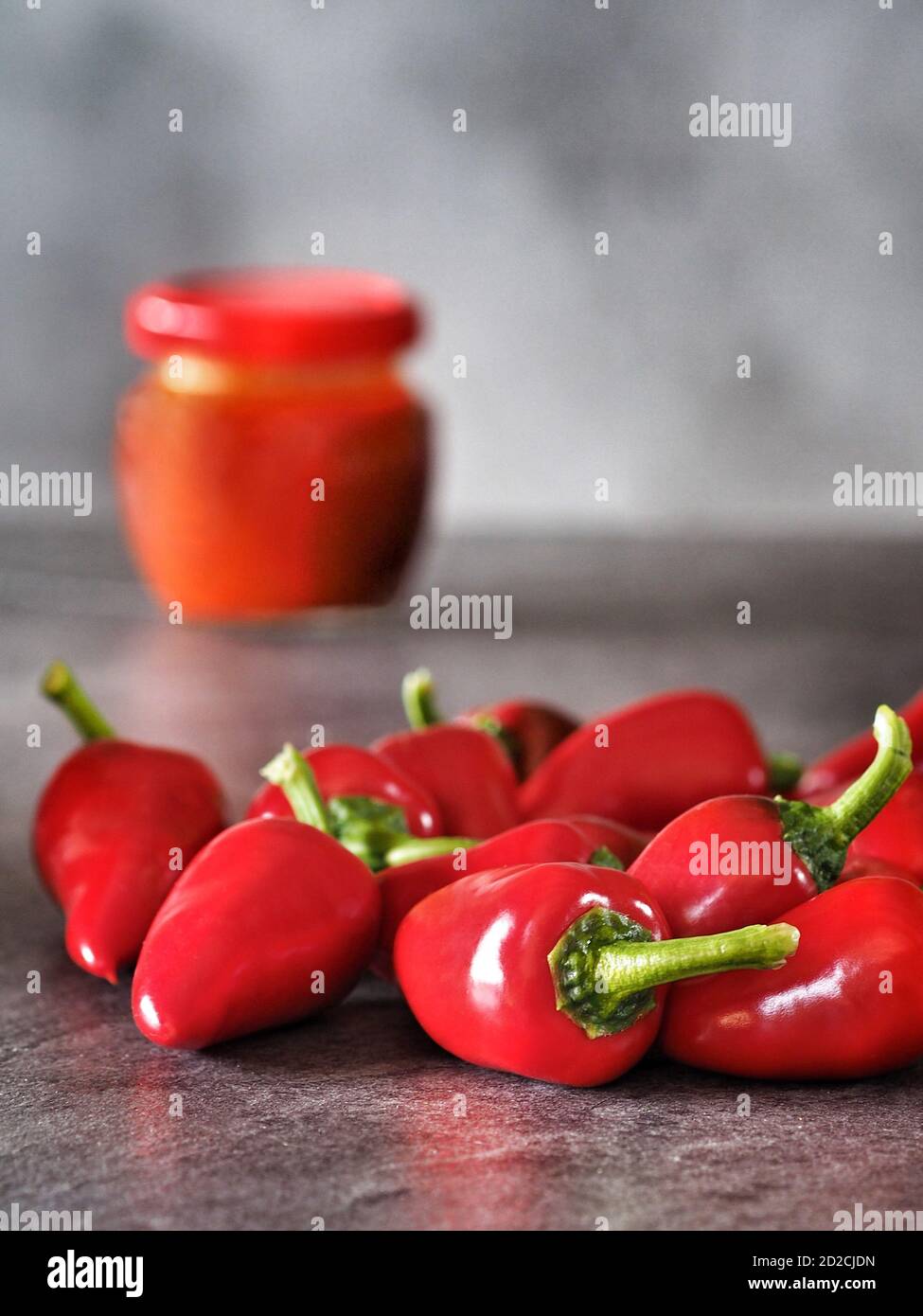 Red hot chilli peppers and ajvar (pepper mousse) on dark background ...