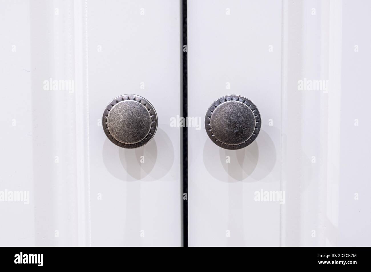 Metal round handles on a white half-open door, close-up Stock Photo - Alamy