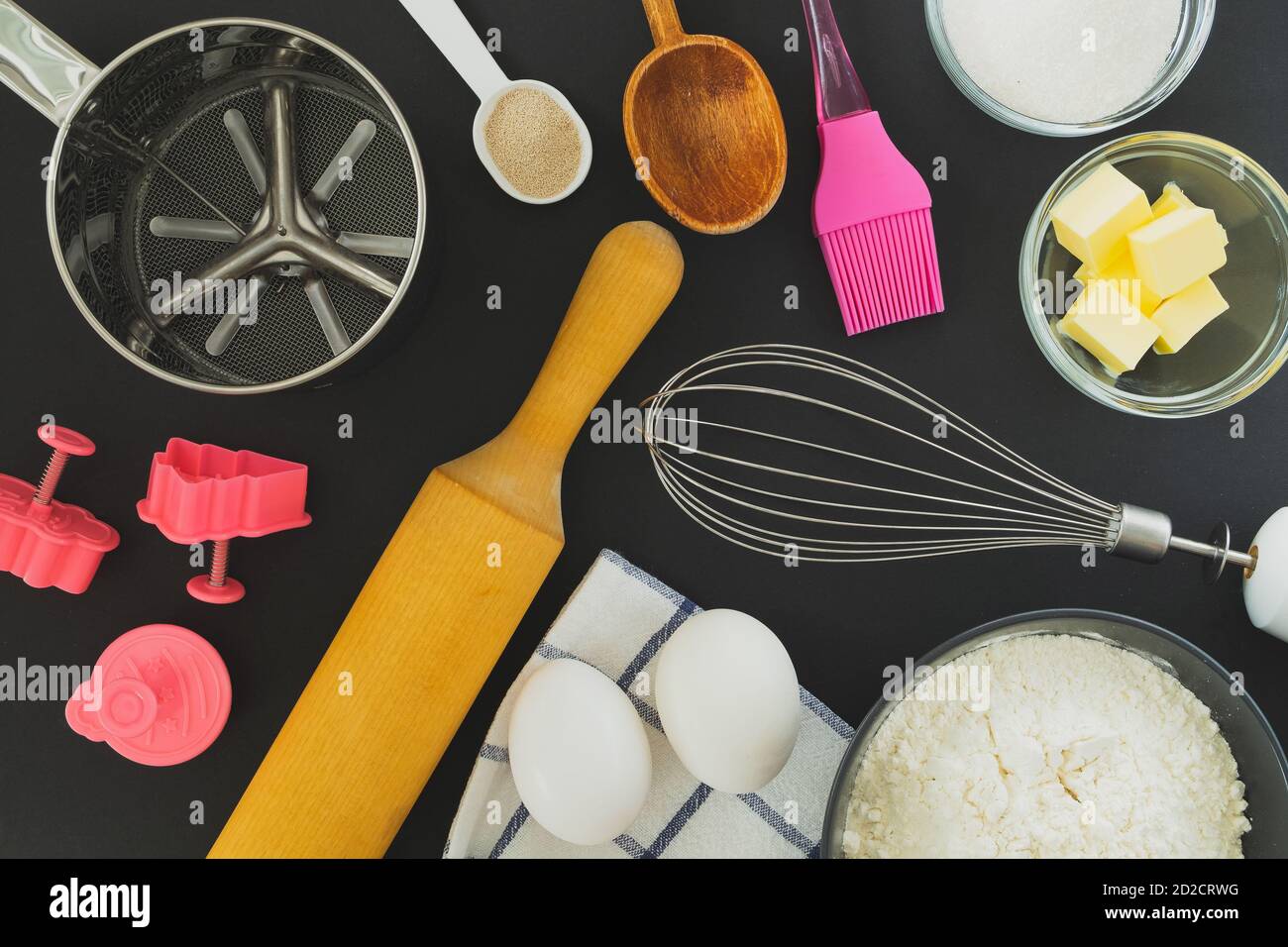 Flat lay ingredients for baking and kitchen utensils on a black ...