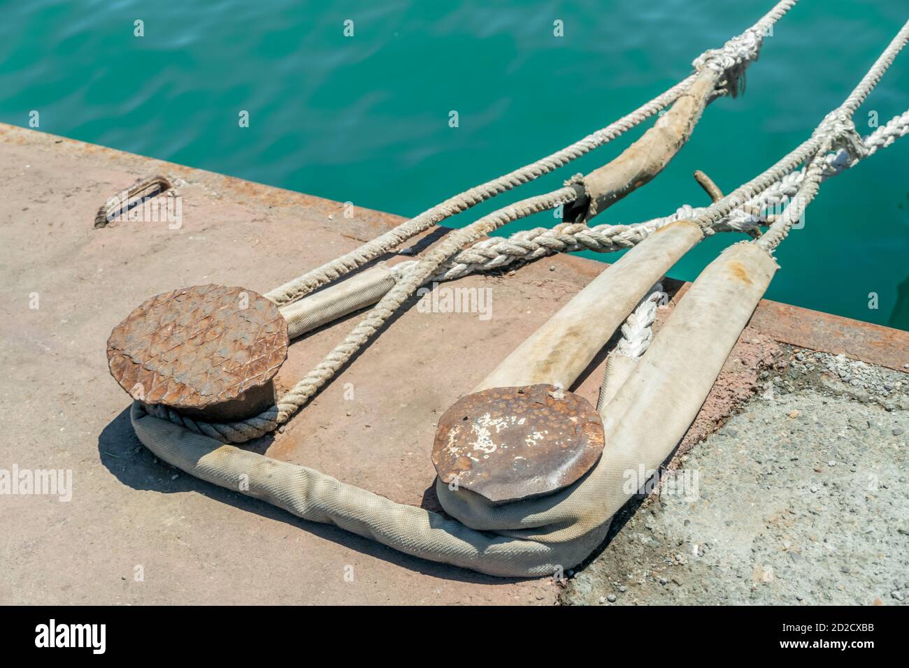 Shore bits with white ropes. Close up view of a steel bollard in a dock ...