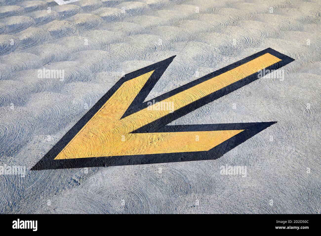 Large yellow and black arrow painted on concrete Stock Photo - Alamy