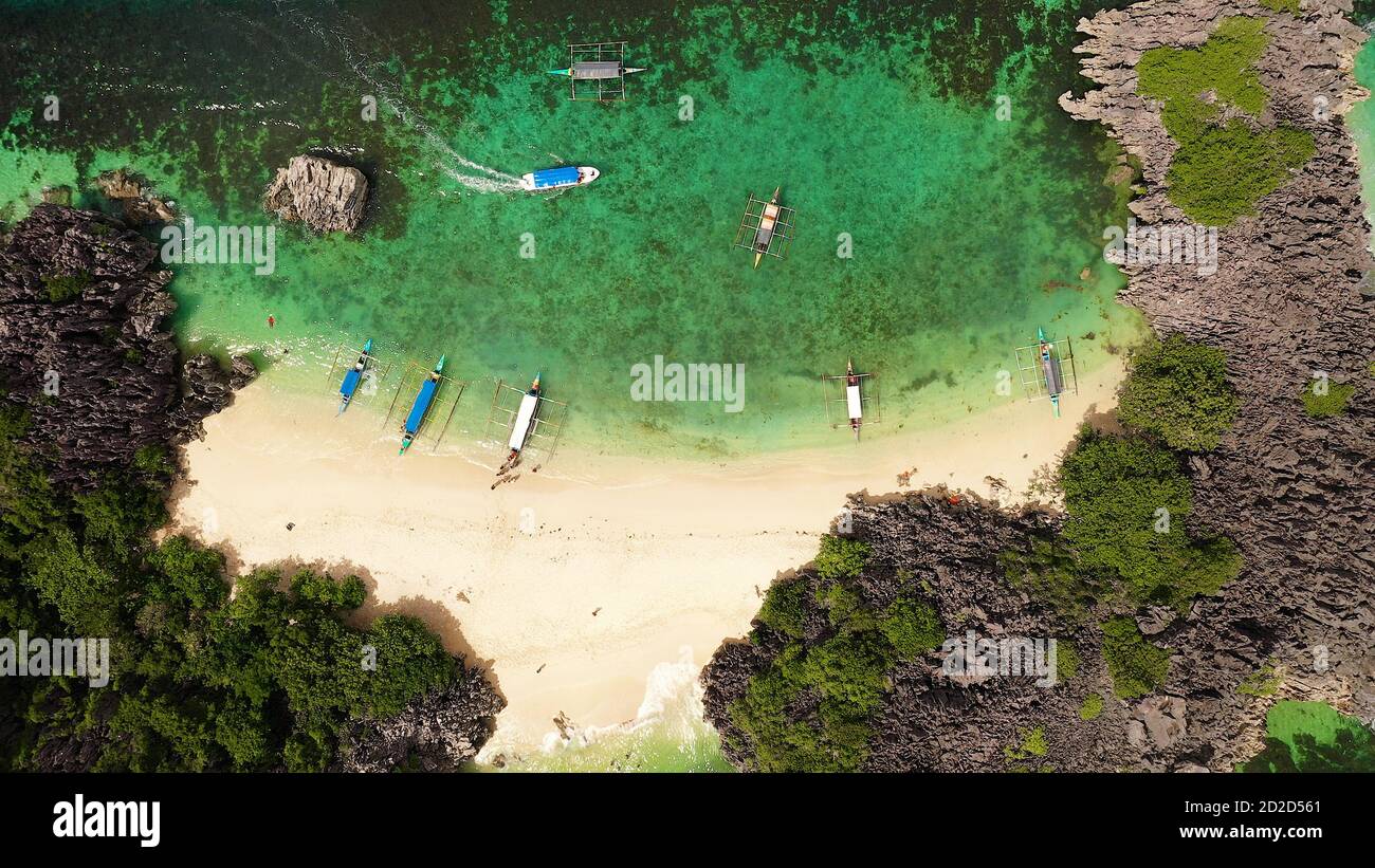 Sandy beach with tourists and tropical island by atoll with coral reef ...