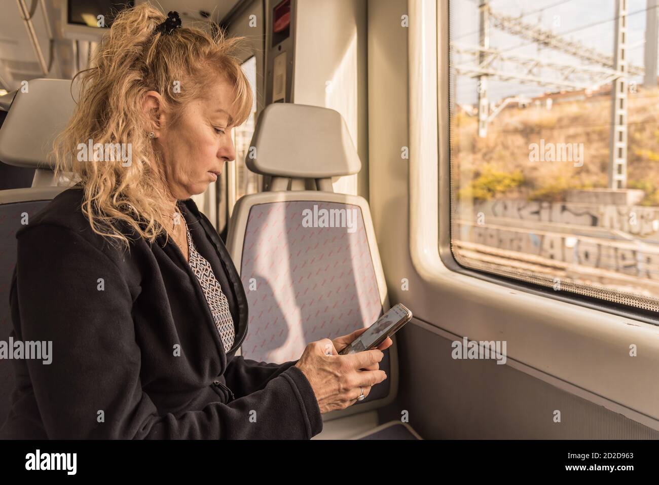 Adult woman traveling alone on the train looking at a mobile. Concept ...