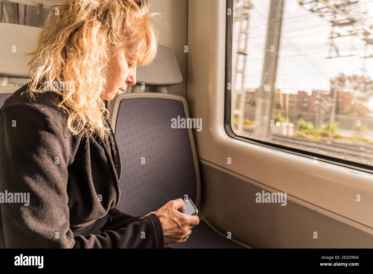 Adult woman traveling alone on the train looking at a mobile. Concept ...