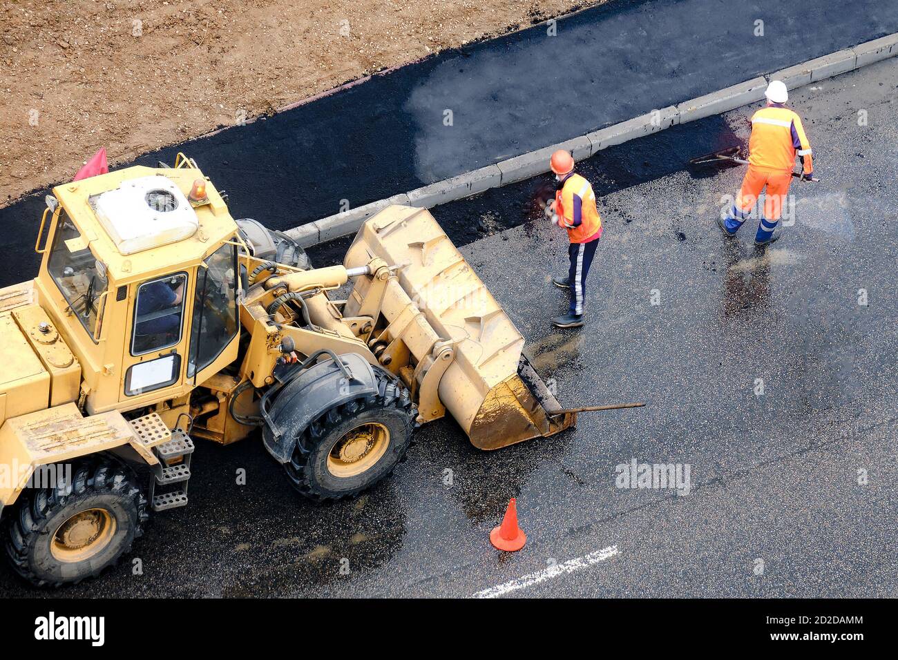 Asphalt a new on the road. Men and a excavator on laying of asphalt ...