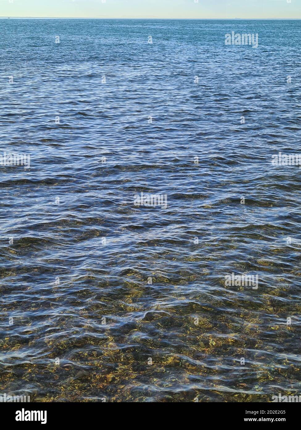Vertical shot of a calm seascape view with pure transparent water with ...