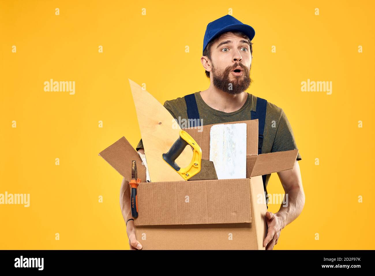 A man in a working form a box with loading tools yellow background ...