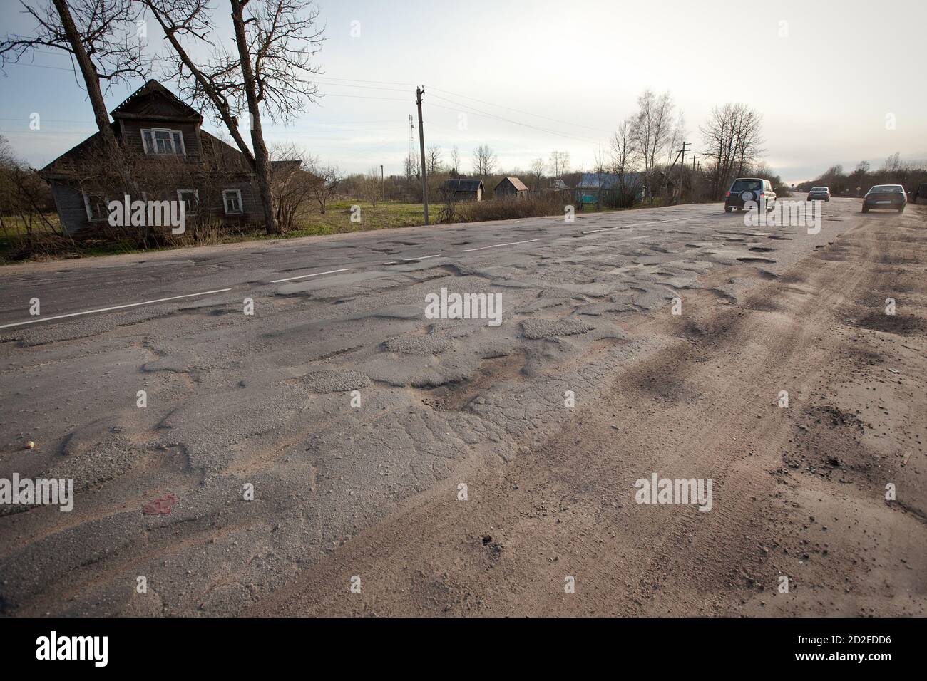Bad quality road with potholes, cars on background, countryside. Hole ...