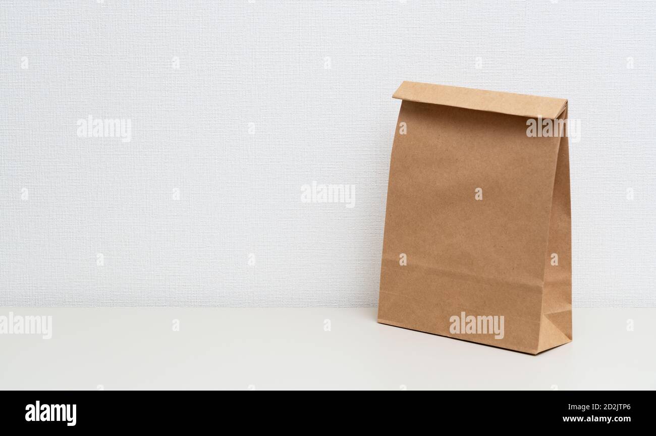 A brown paper bag placed in front of a white wall with space Stock ...