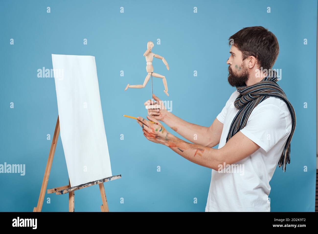 Male artist with a wooden dummy in hands drawing Creative hobby blue ...