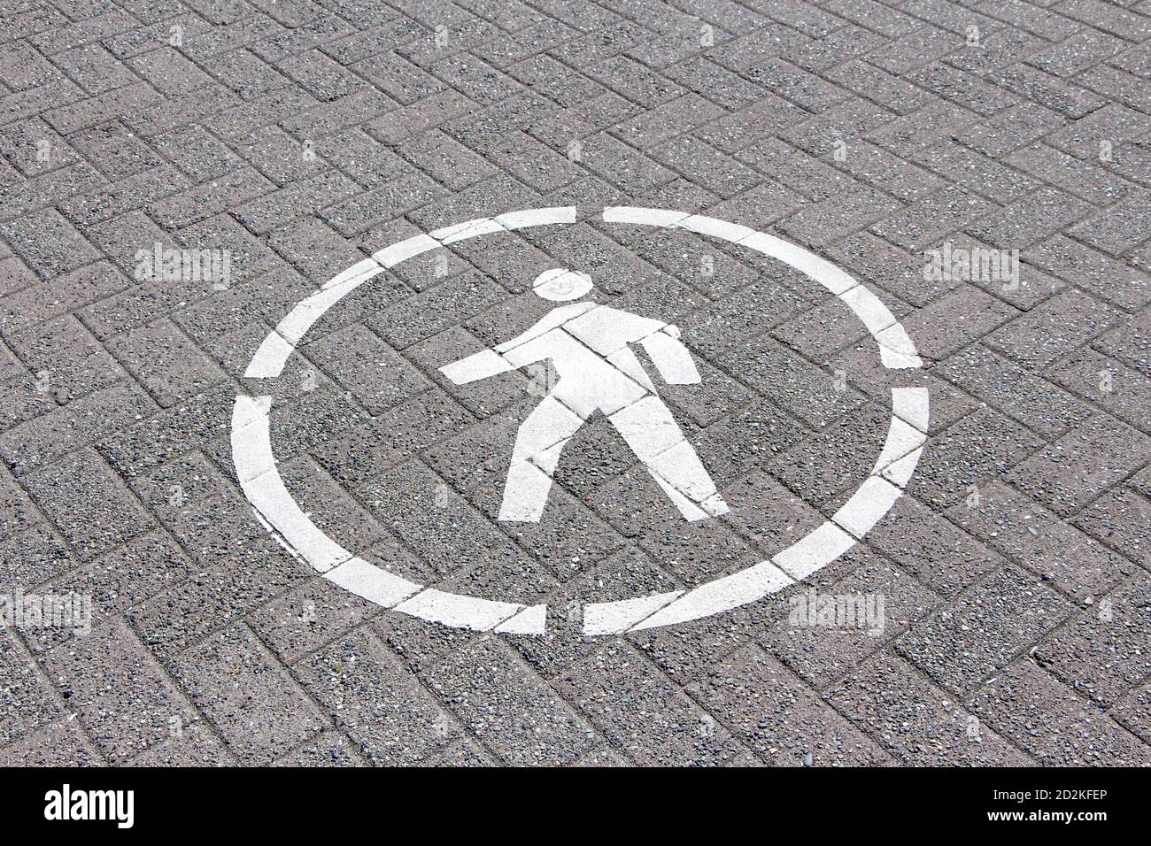 Pedestrian white sign in the circle painted on the brick pathway ...