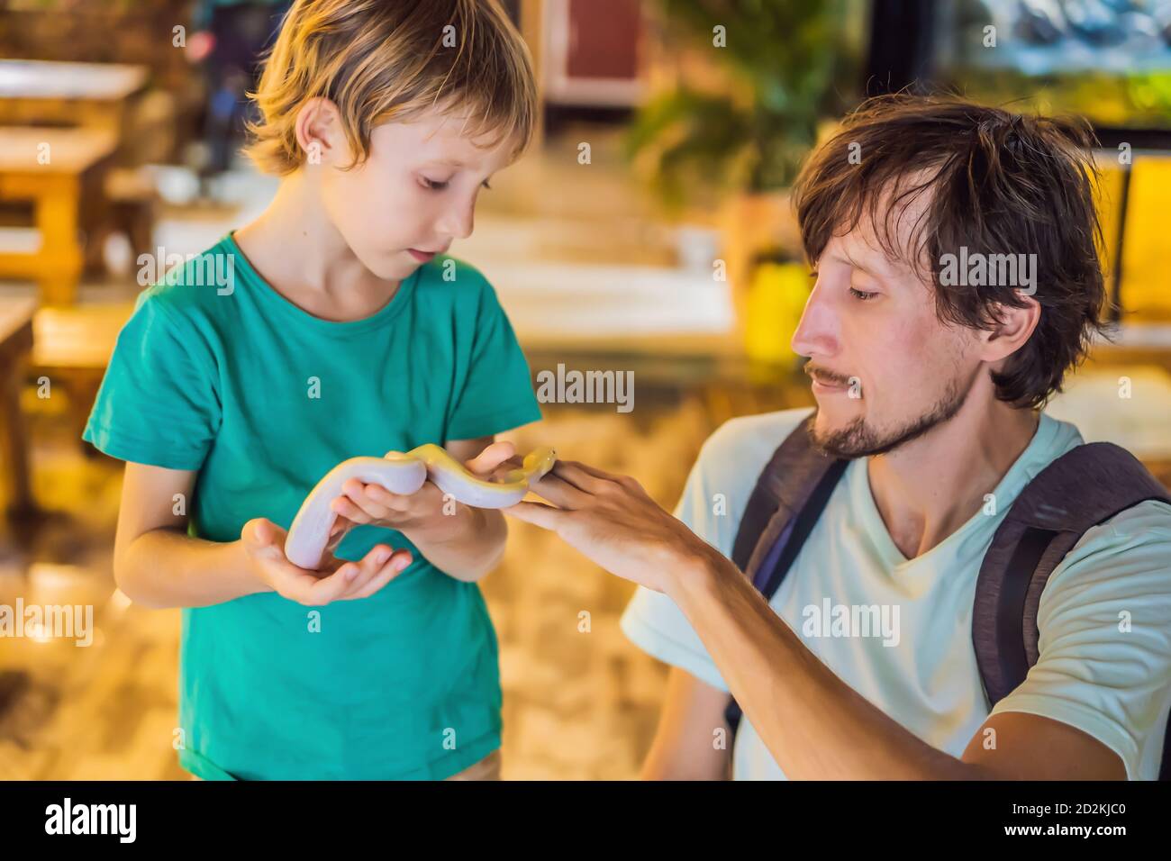 Smiling boy and his father holding python in hands Stock Photo - Alamy