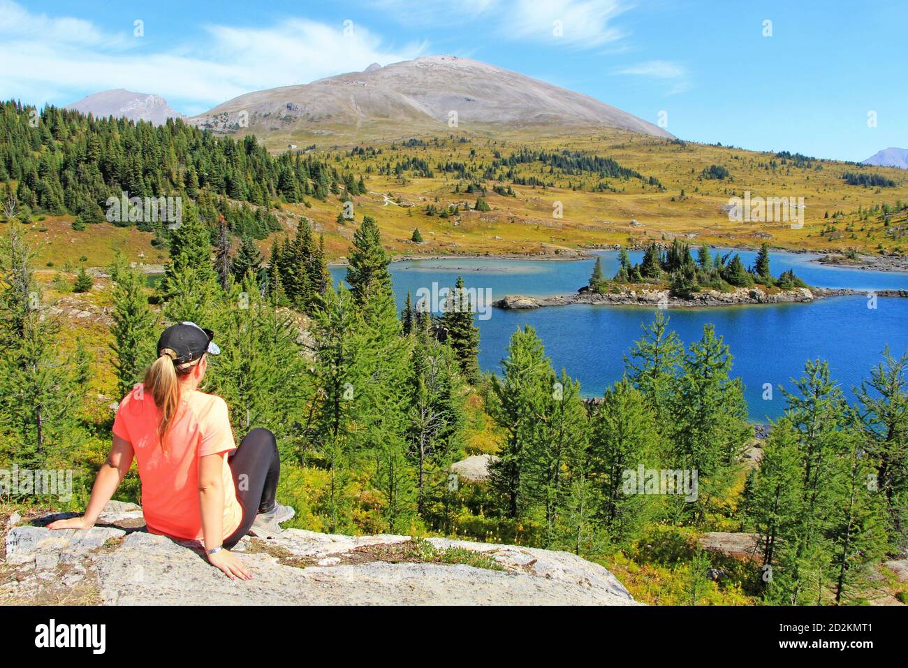 Blonde woman / female hiker sitting on the cliff by beautiful Rock Isle ...