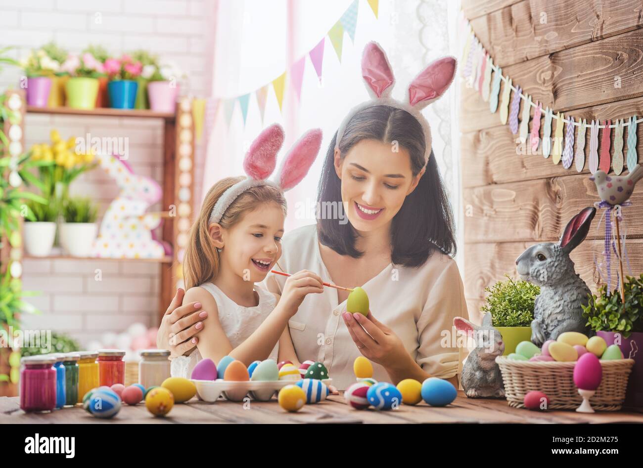 Mother and her daughter painting eggs. Happy family preparing for ...