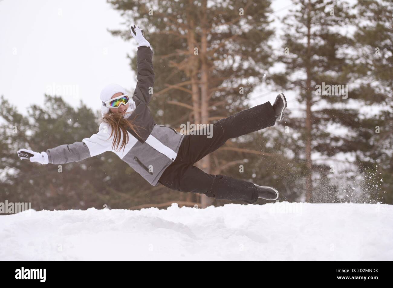happy active little girl in ski suit jumping on white winter snow ...
