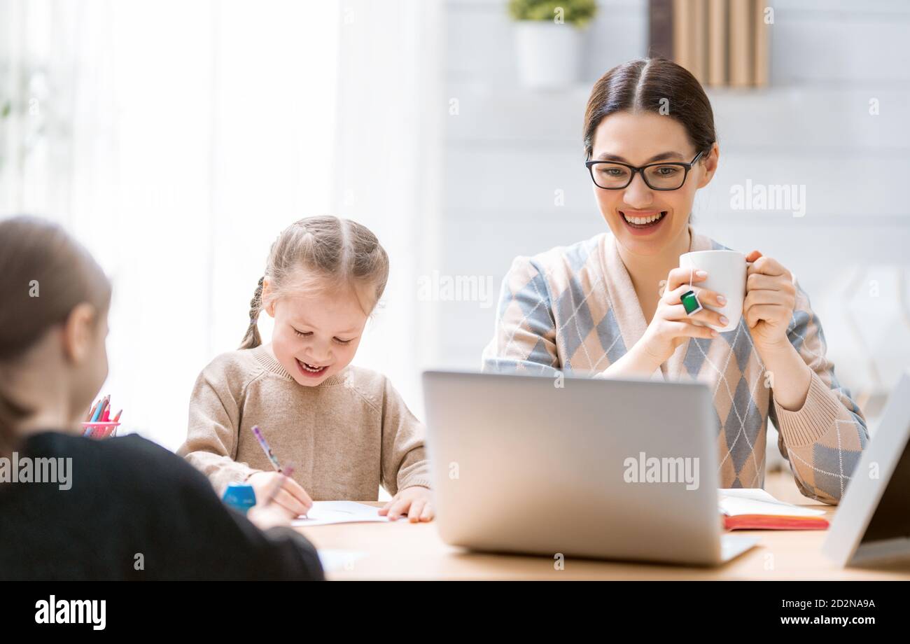 Young mother with children working on the computer. Family at home ...