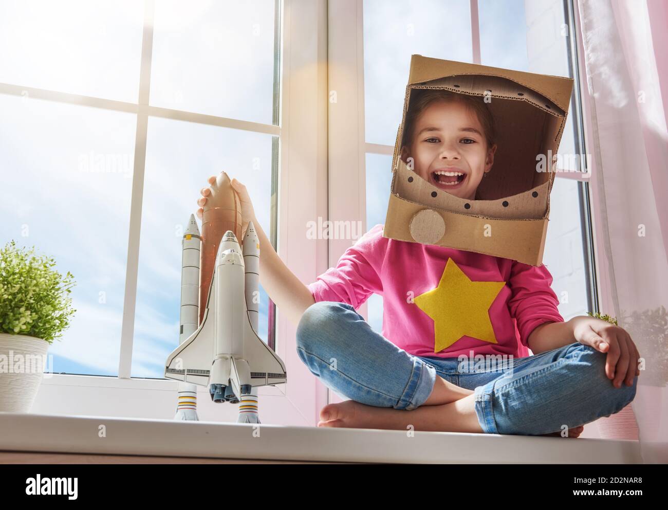 Child girl in an astronaut costume with toy rocket playing and dreaming ...