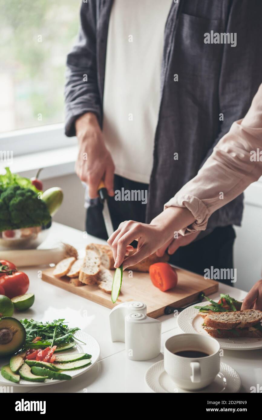 Close up photo of a caucasian couple slicing food in the kitchen ...
