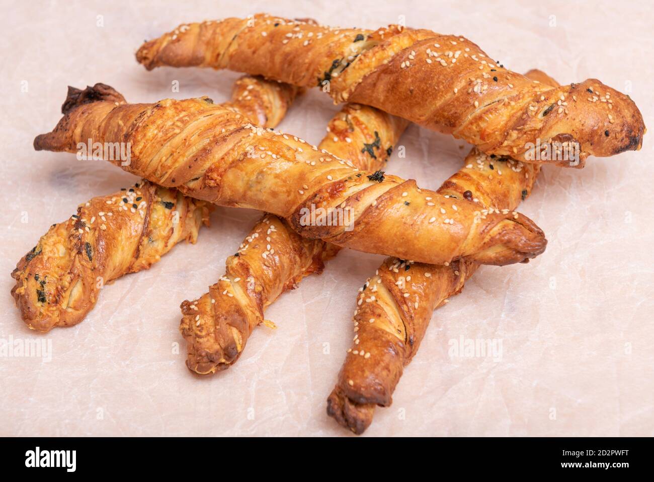 Twisted puff pastry sticks on white paper parchment, wood table Stock ...