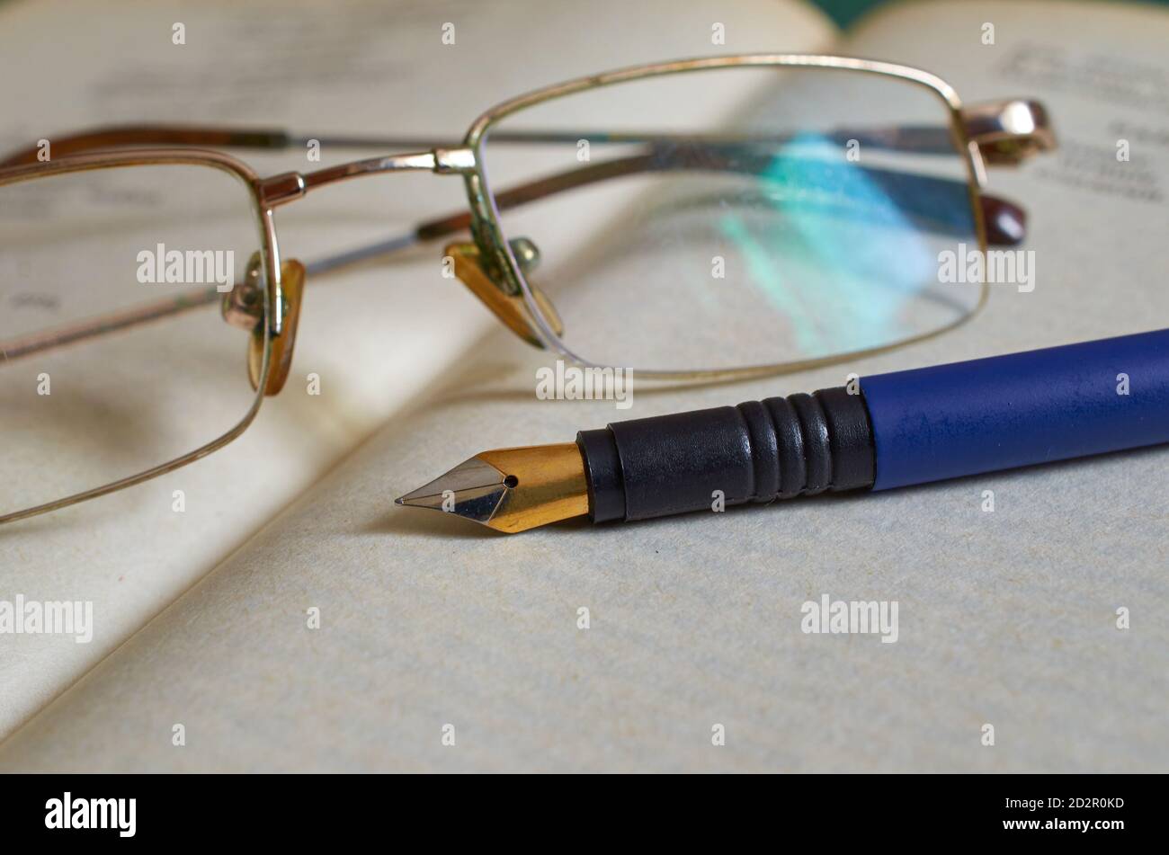 Glasses and a blue fountain pen lie on an open book. Close up Stock ...