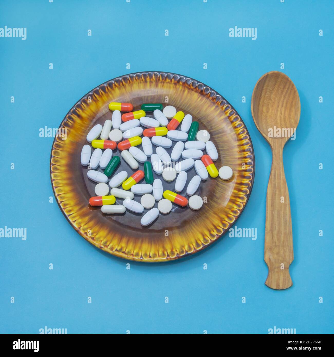 Medication pills and capsules on plate and spoon. Blue background ...