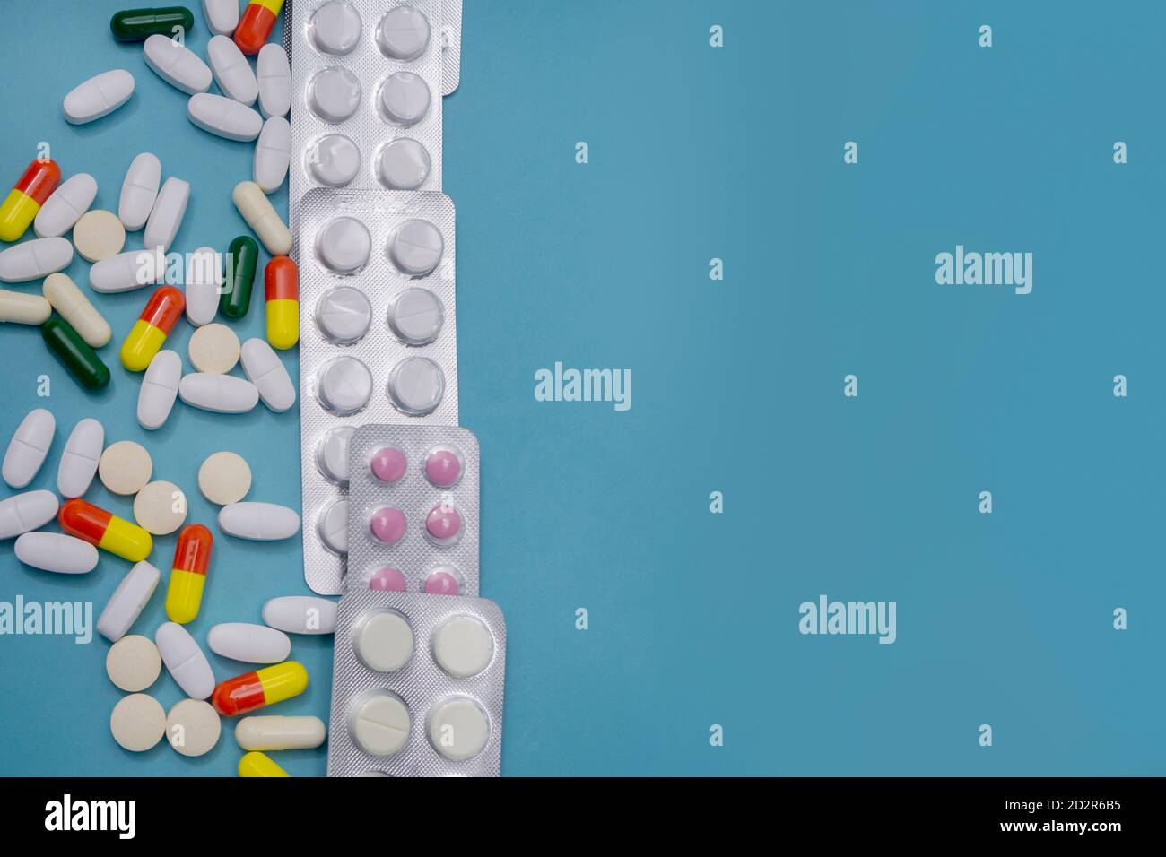 Various tablets and capsules of drugs. Blue background, copy space ...